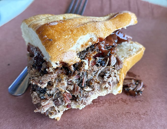 This pulled pork sandwich isn't just a meal&mdash;it's an architectural achievement of tender, smoky meat threatening to escape its bread boundaries.