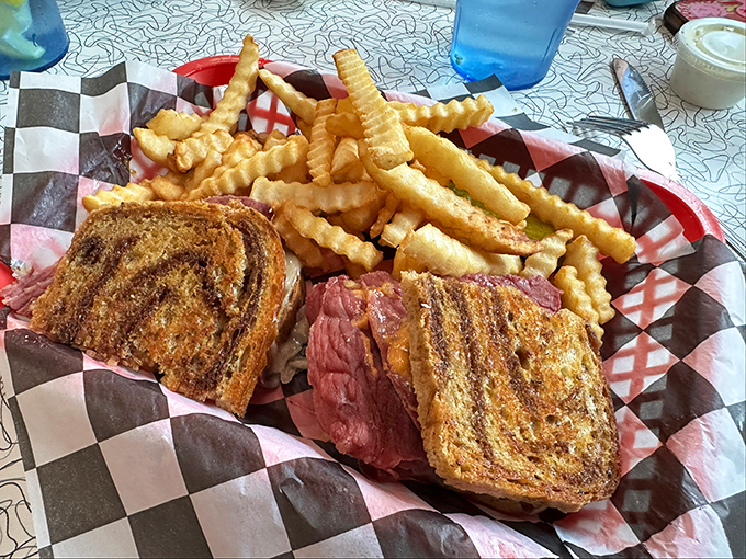 The Reuben sandwich in its natural habitat&mdash;perfectly grilled rye, meat stacked higher than your weekend plans, surrounded by a golden moat of crinkle-cut fries.