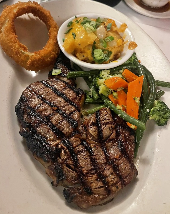 A perfectly grilled steak with textbook grill marks that would make a geometry teacher proud. The onion ring crown adds necessary drama.