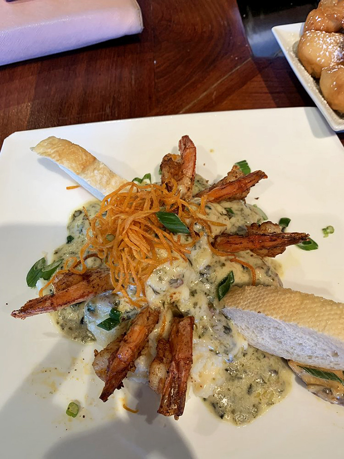 The Grits a Ya Ya arrives like a crown jewel&mdash;spiced shrimp standing at attention over creamy grits, with crispy garnish adding the perfect textural counterpoint.