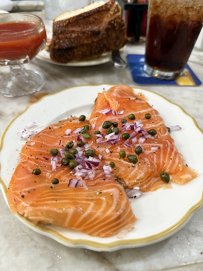 Salmon sashimi adorned with capers and red onion &ndash; a silky, coral-colored canvas painted with simple ingredients that somehow create a masterpiece.