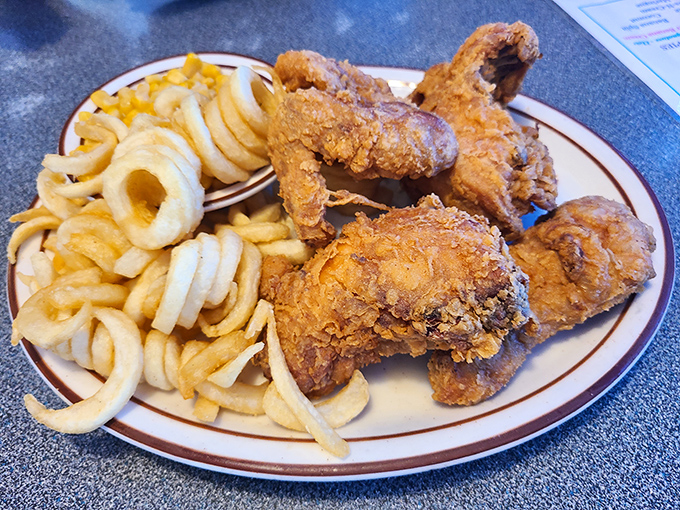 Southern fried chicken with a golden crust that shatters like vinyl records in a tantrum, paired with curly fries that could double as edible Slinkys.