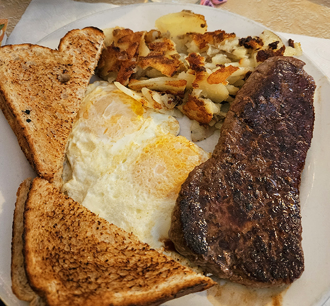 The holy trinity of breakfast: perfectly seared steak, eggs with yolks ready to burst, and hash browns with that ideal crisp-to-tender ratio that chain restaurants can't replicate.