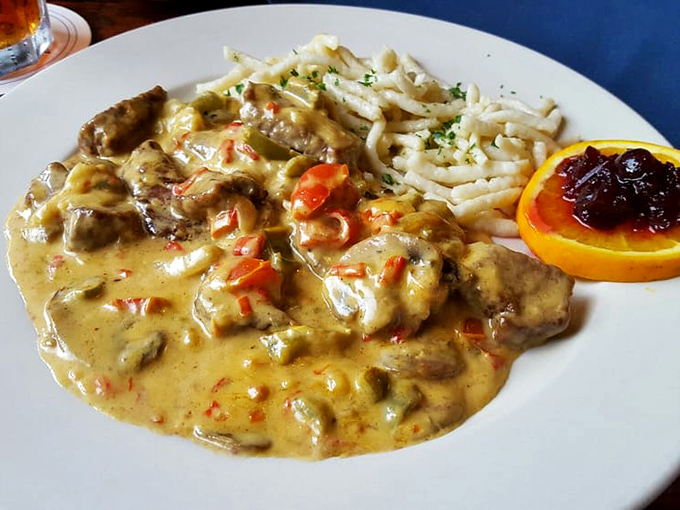 Not your cafeteria stroganoff! Tender meat swimming in a rich, creamy sauce dotted with colorful peppers, alongside perfectly cooked spätzle and a bright citrus garnish.