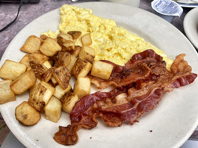 The holy trinity of breakfast perfection: crispy bacon, fluffy scrambled eggs, and home fries that could make a potato proud