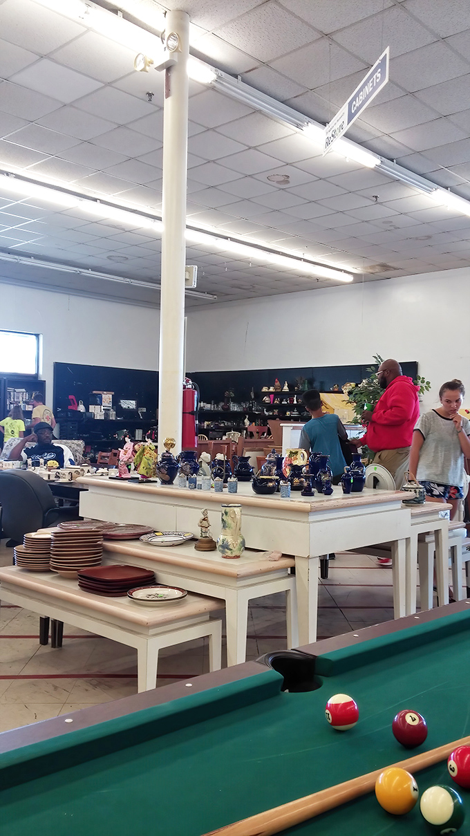 The "Resource Center" sign hangs above shoppers browsing tabletop treasures. One person's decluttering becomes another's decorating jackpot.