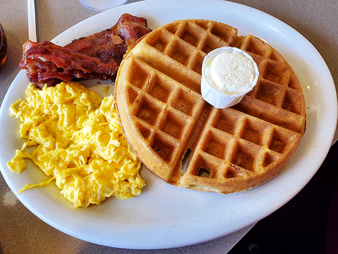 The breakfast trinity: golden waffle, fluffy scrambled eggs, and bacon that actually tastes like bacon. Morning salvation on a plate.