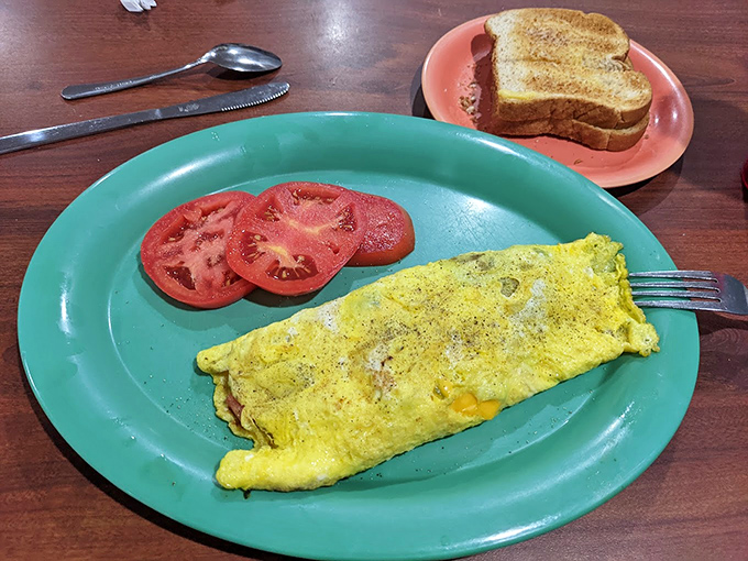 Breakfast dreams are made of this: a perfectly executed omelet with fresh tomato slices and toast ready for buttery transformation.