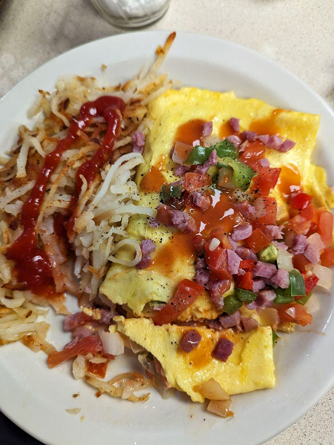 This isn't just an omelet; it's a colorful celebration of morning possibilities with hash browns that achieve the perfect crisp-to-tender ratio.