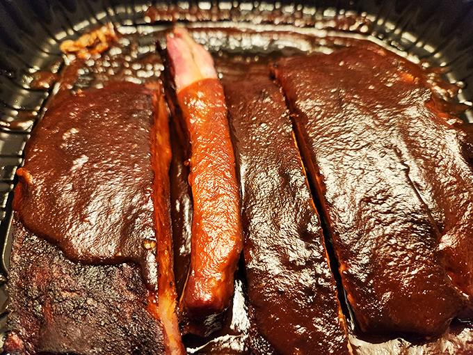 These ribs aren't just glazed &ndash; they're wearing a mahogany lacquer that would make fine furniture jealous, with smoke rings that tell tales of patience.
