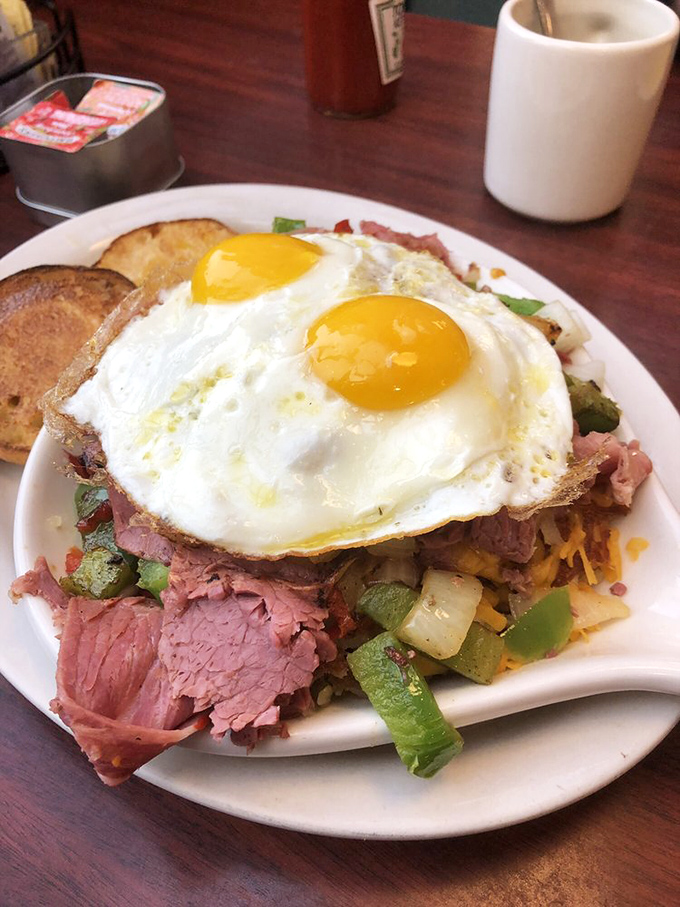A breakfast mountain worthy of conquering—perfectly cooked eggs crowning a colorful landscape of hash and ham.