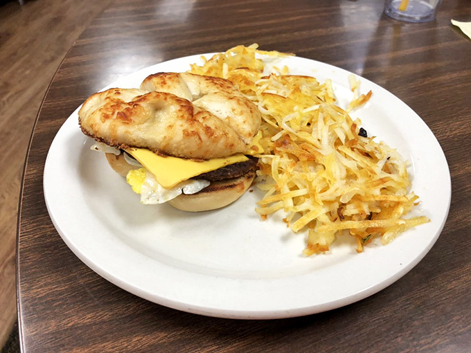 Breakfast sandwich perfection: a golden English muffin embracing eggs and cheese, with crispy hash browns standing guard alongside.