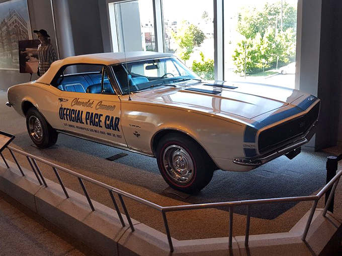 The Chevrolet Camaro Official Pace Car sits regally on display, its cream finish and racing stripes a testament to America's love affair with muscle and speed.