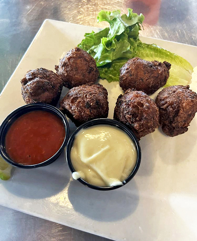 Golden-brown conch fritters that crunch like your favorite childhood memory, served with dipping sauces worth fighting over.