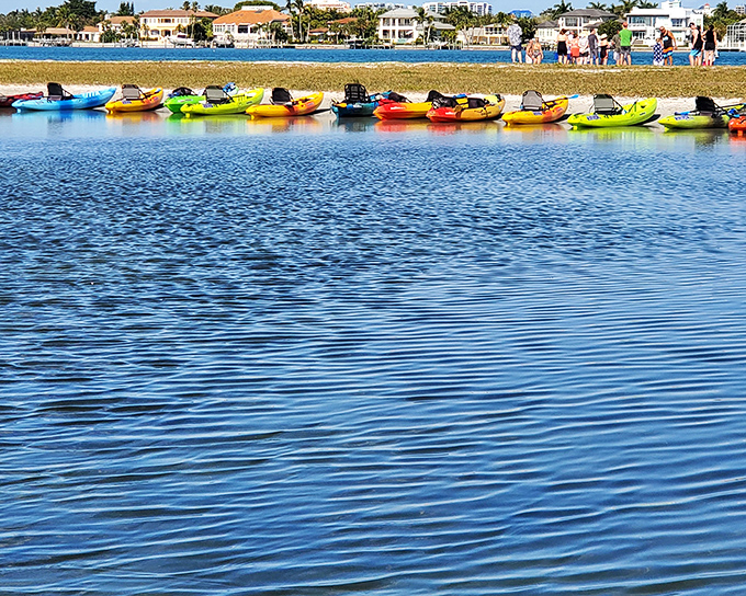 A rainbow of kayaks waiting for their next adventure. Like a box of crayons for grown-ups who prefer drawing their own paths through water.