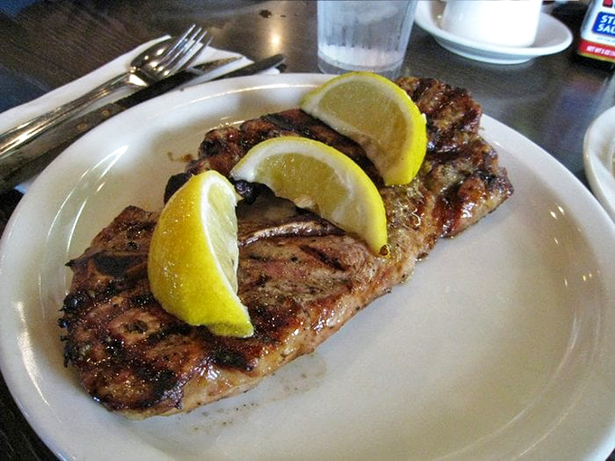 Pork chops that would make your grandmother proud, served with bright lemon wedges that cut through the richness like a well-timed punchline.