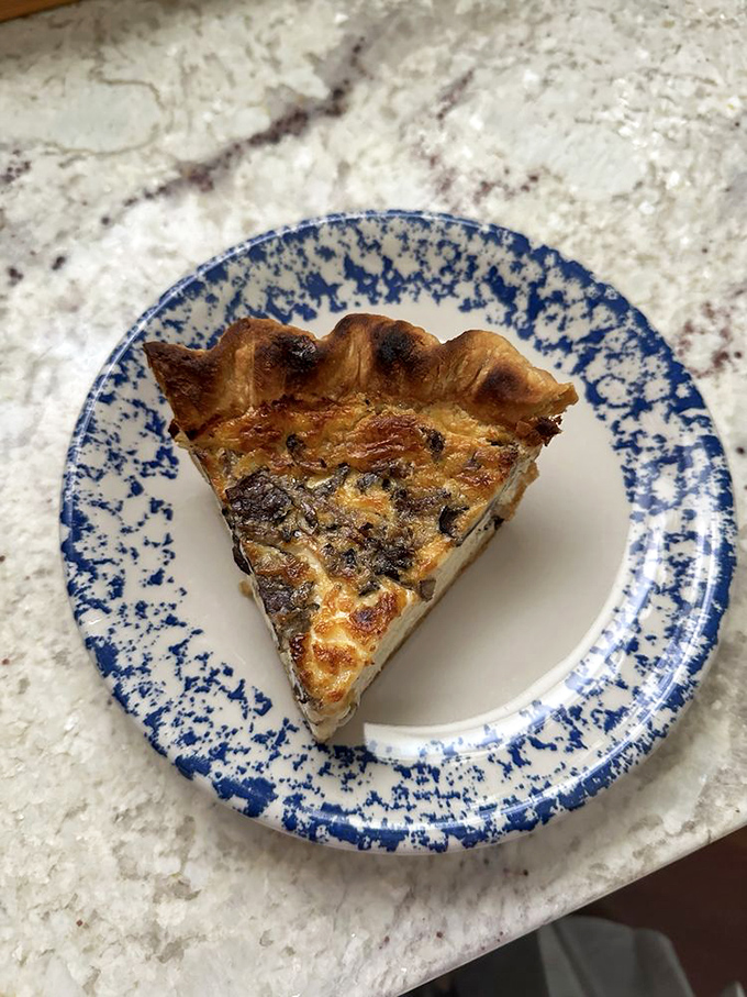 A perfect quiche slice on blue-speckled china, proving that eggs and pastry make beautiful music together.