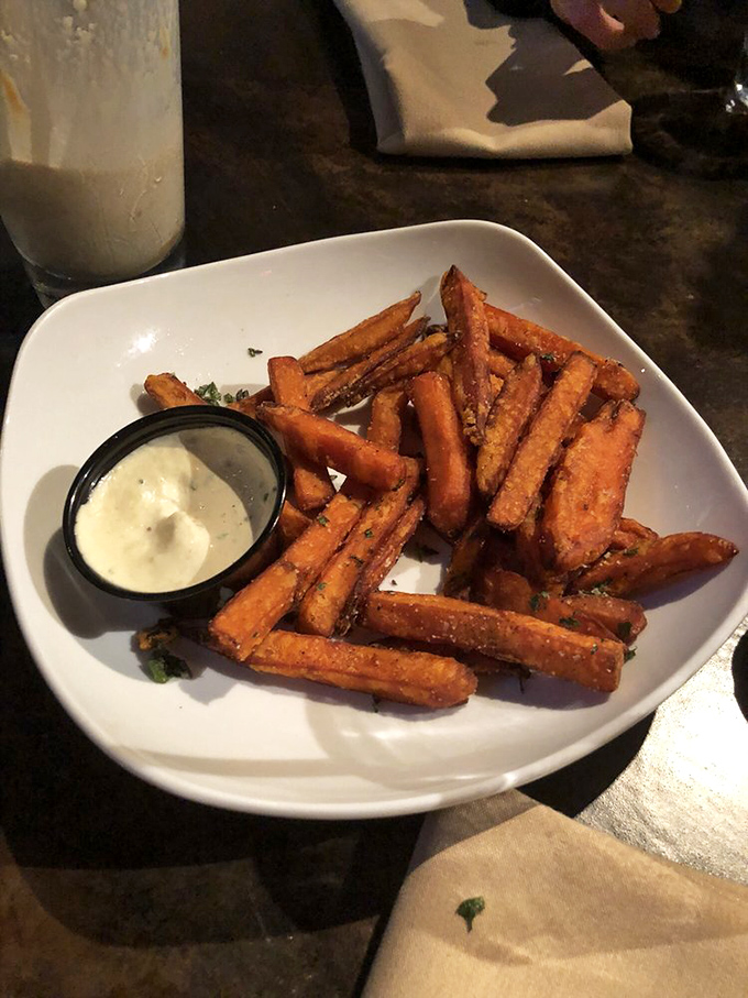 Sweet potato fries that achieve the impossible: crispy exterior, pillowy interior, and a dipping sauce worth bottling and selling on the black market.