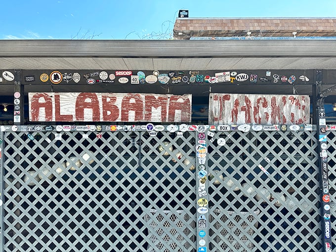 The lattice wall tells stories of decades past – each sticker a memory, each weathered board a testament to survival.