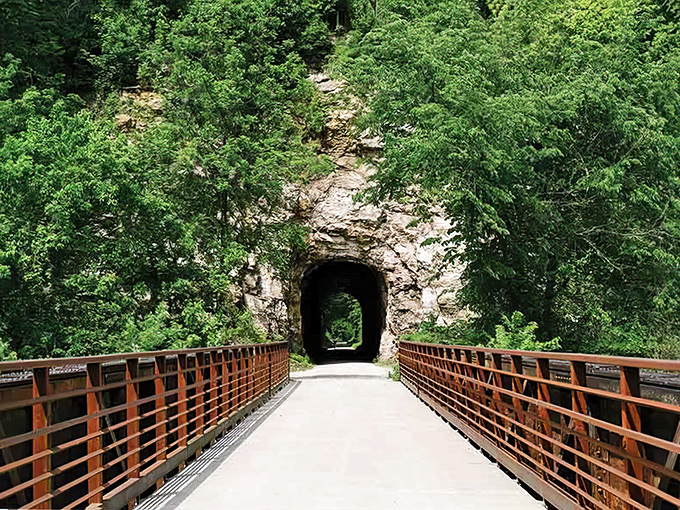 Nature reclaims the railroad tunnel where hikers and cyclists discover Missouri's hidden gem along the scenic river. P