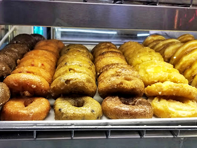 A rainbow of cake donuts standing at attention, like delicious soldiers ready for their noble mission to brighten your morning.
