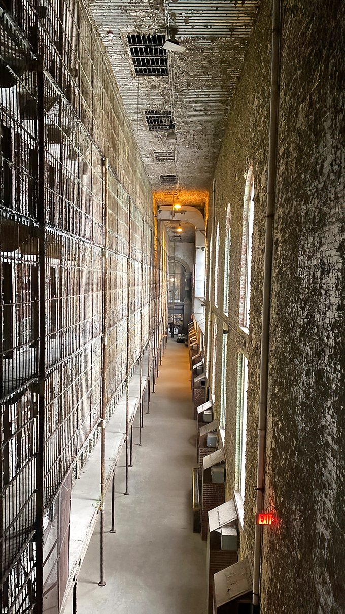 Looking down the cell block corridor feels like peering into another dimension. Sunlight creates prison-bar shadows that seem almost poetic. 