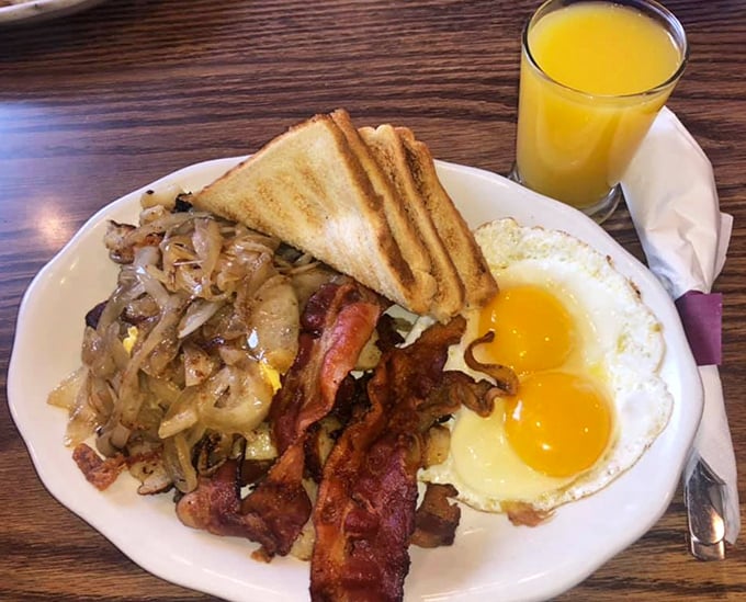 Breakfast perfection: golden home fries mingling with crispy bacon and sunny-side-up eggs that practically high-five your taste buds.
