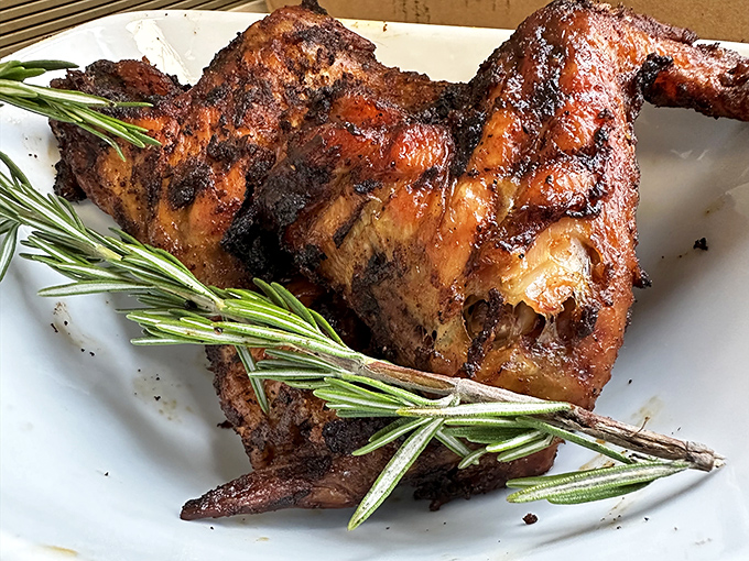 Rosemary-garnished BBQ chicken with skin that crackles like nature's potato chip before surrendering to juicy meat beneath.