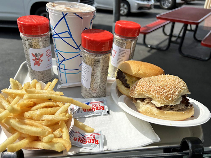 The classic combo that launched a thousand road trips: burger, fries, and those signature seasoning shakers that somehow make everything taste better.