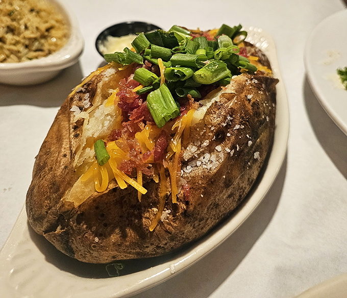 The humble baked potato elevated to art form – a volcanic mountain of starchy goodness erupting with cheese, bacon, and green onions.