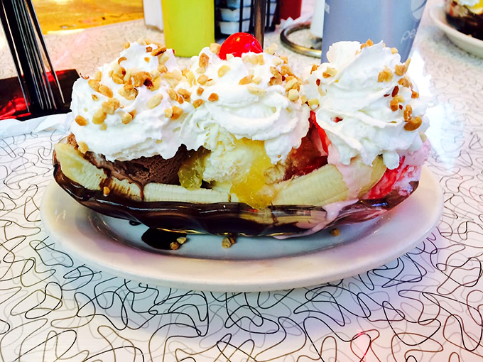 Ice cream architecture at its finest &ndash; a towering monument to sweetness where bananas, whipped cream, and nuts come together in perfect harmony.