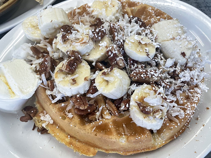 Waffle perfection topped with bananas, pecans, and a dusting of powdered sugar &ndash; like a tropical vacation that fits on a fork.