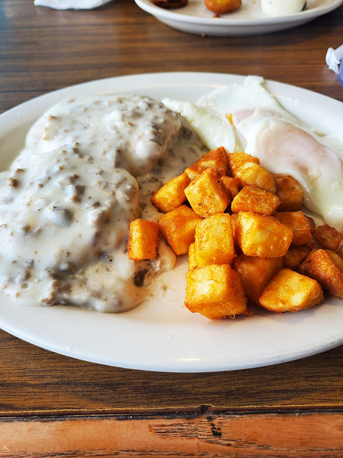 The holy trinity of diner breakfast: biscuits drowning in sausage gravy, home fries crisped to perfection, and eggs that know exactly who they are.