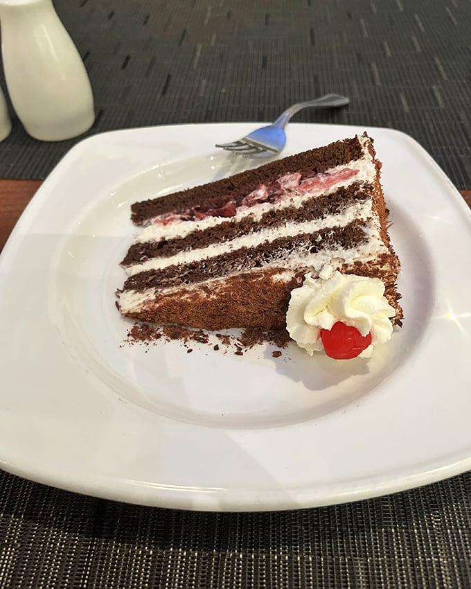 The Black Forest cake layers tell a delicious story: chocolate chapters separated by cherry-studded cream bookmarks, with a whipped cream epilogue.