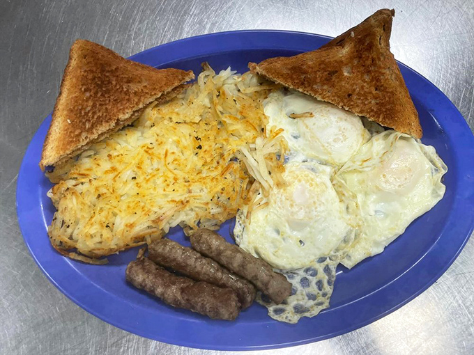 Breakfast perfection on a blue plate: golden hash browns, eggs with just-right yolks, and toast waiting for its butter bath. This is why alarm clocks were invented.