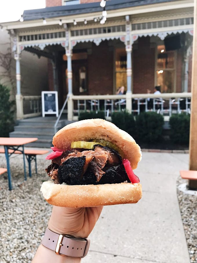 The sandwich that launched a thousand napkins. This brisket creation, framed by the Victorian porch, is Columbus architecture meeting meat architecture.