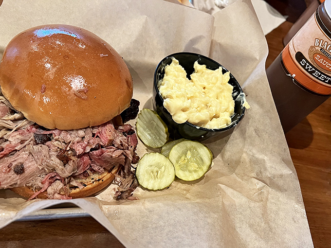 A sandwich that requires both hands and a strategy: pulled meat piled high with pickle coins standing guard, ready to cut through all that smoky richness.