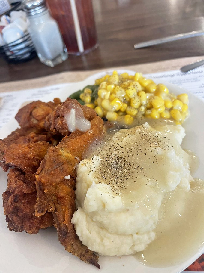 Fried chicken that would make Colonel Sanders question his life choices, nestled beside mashed potatoes and corn that actually tastes like corn.