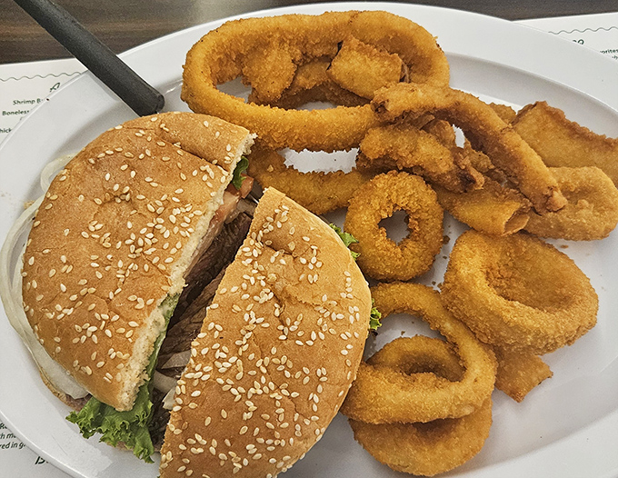 A burger that means business, surrounded by golden onion rings like delicious life preservers in a sea of flavor.