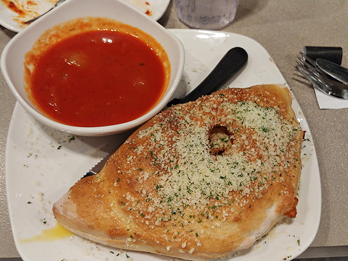 Not all heroes wear capes, but this calzone wears a dusting of parmesan and herbs that deserves its own superhero theme music.
