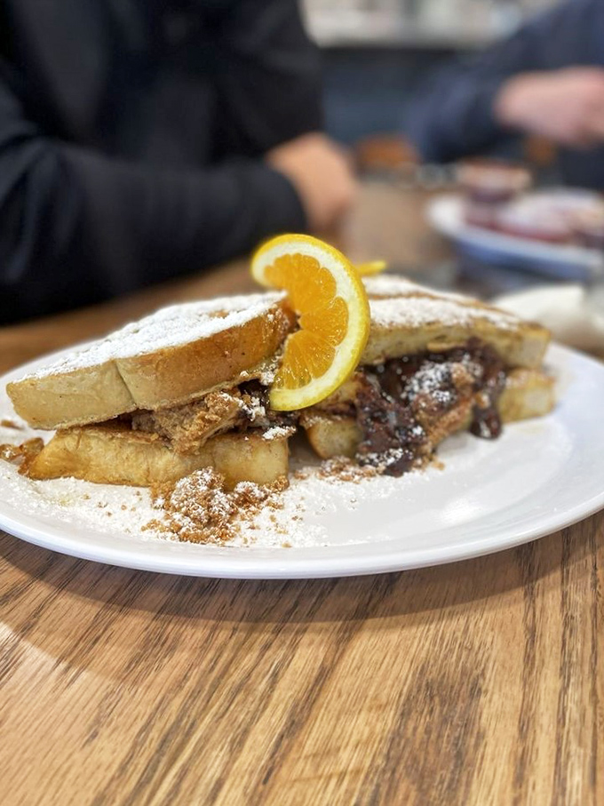 French toast that's having an identity crisis as cheesecake—powdered sugar, cinnamon, and that orange slice pretending this is somehow breakfast.