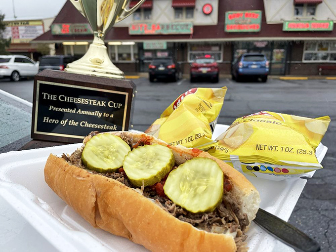 The Cheesesteak Cup trophy watches over a sandwich worthy of accolades—pickles standing guard over tender meat like delicious sentinels.