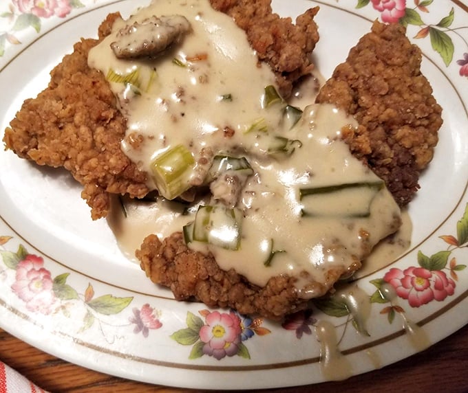 Country fried steak smothered in gravy with green onions&mdash;where crunch meets creamy in a Southern dance that's been perfecting its moves for generations.