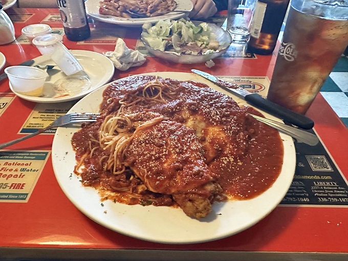 Chicken Parmesan arrives like edible architecture, towering over spaghetti with golden, crispy perfection.