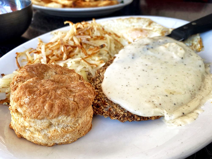 Behold: the chicken fried steak in its natural habitat, accompanied by a flaky biscuit. That pepper-speckled gravy should have its own fan club.