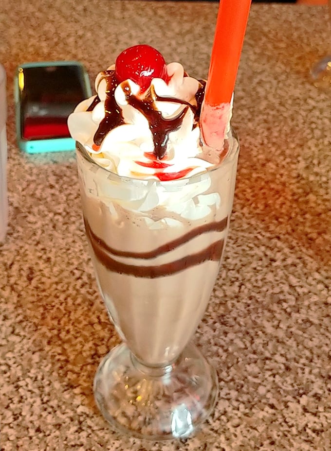 This milkshake doesn't just bring boys to the yard—it establishes residence there. Whipped cream, cherry, and that impossibly tall straw.