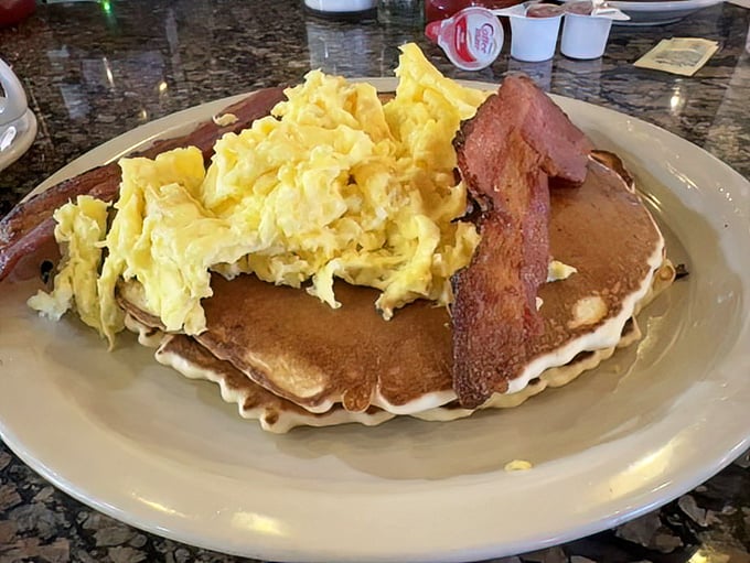 The breakfast trifecta: fluffy pancakes, perfectly scrambled eggs, and bacon that's achieved that magical balance between crisp and chewy. Morning nirvana achieved.