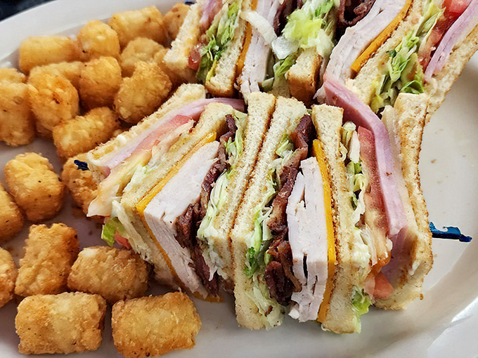 The club sandwich&mdash;mankind's greatest achievement after fire and the wheel. Triple-decker comfort with tater tots that crunch like childhood memories.