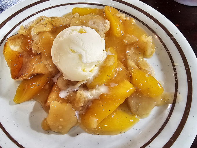 Peach cobbler topped with vanilla ice cream—the dessert equivalent of a warm hug from someone who truly understands you.