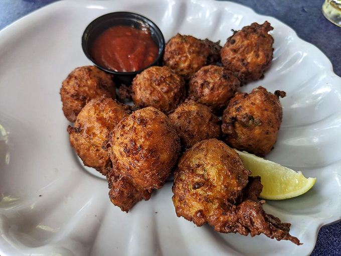 Golden-brown conch fritters that crackle with each bite, revealing a tender, savory interior. The lime wedge isn't just garnish&mdash;it's essential.